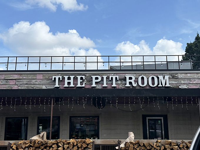The Pit Room's rustic sign stands proudly against a blue sky, welcoming hungry visitors to this Houston barbecue haven.