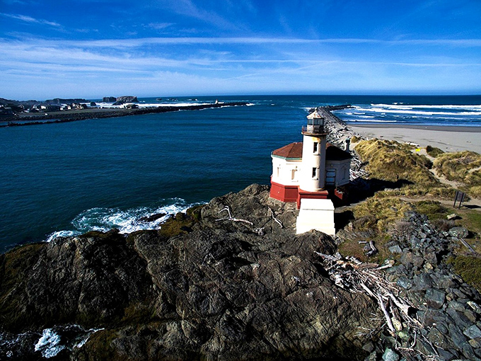 The Coquille Lighthouse stands like a maritime sentry, its red-and-white profile a perfect backdrop for those "look, I'm holding up the lighthouse" photos everyone secretly loves.