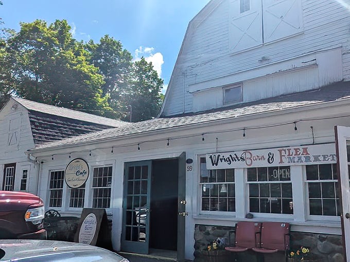 Classic white barn architecture meets flea market magic. The string lights hint at the warm welcome waiting just beyond those vintage doors.