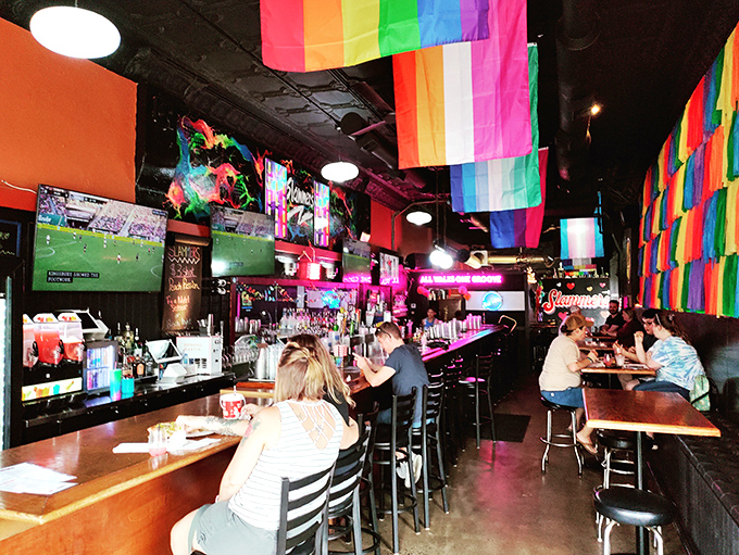 Rainbow flags create a ceiling of inclusion above the bar, where cocktails flow and conversations buzz in this vibrant Columbus gathering spot.