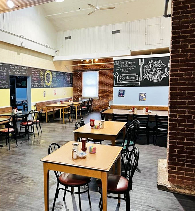 Exposed brick meets chalkboard menus in this cozy dining space where breakfast dreams come true. The simple wooden tables are stages for bacon-forward masterpieces.