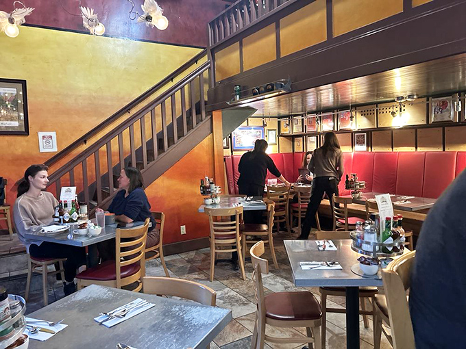 Warm golden walls, wooden staircases, and red booth seating create the perfect backdrop for morning conversations and coffee refills.