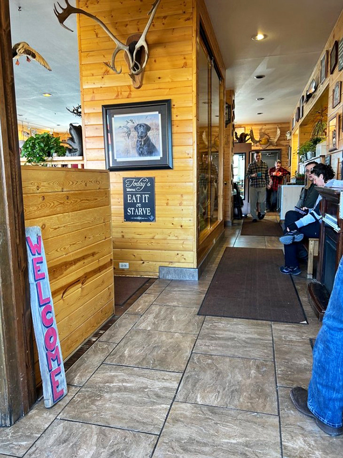 "Eat It Or Starve" isn't just a sign—it's a philosophy. The warm wood interior and mounted antlers tell you immediately: this is Alaska, not some big-city brunch spot.