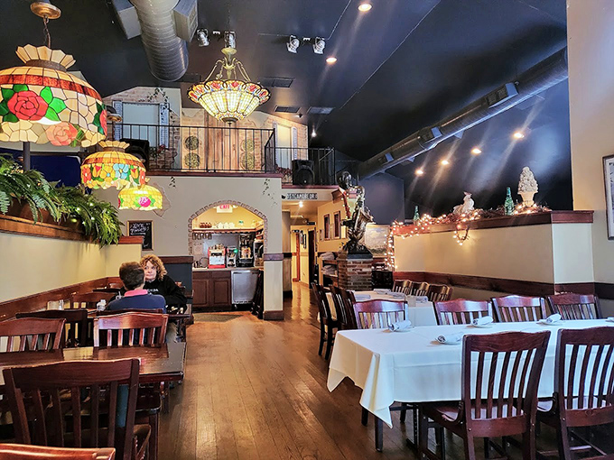 Tiffany-style lamps cast a warm glow over wooden tables. The split-level dining room feels like the cozy living room of that friend who actually knows how to cook.