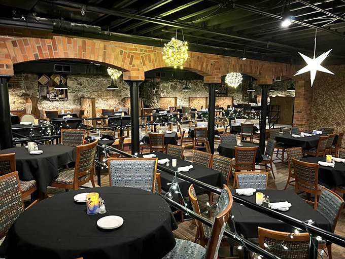 Stone walls, brick arches, and twinkling lights create a romantic grotto atmosphere that whispers, "Stay awhile and savor something special."