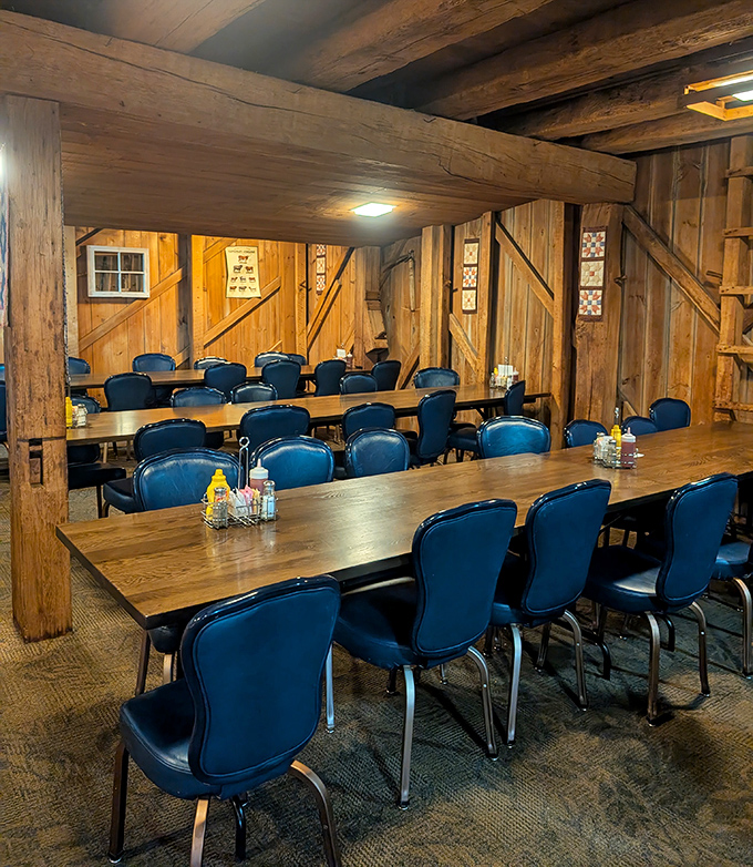 Exposed wooden beams and rustic walls create a dining space that feels both cathedral-like and cozy. Those blue chairs add just the right pop of color.