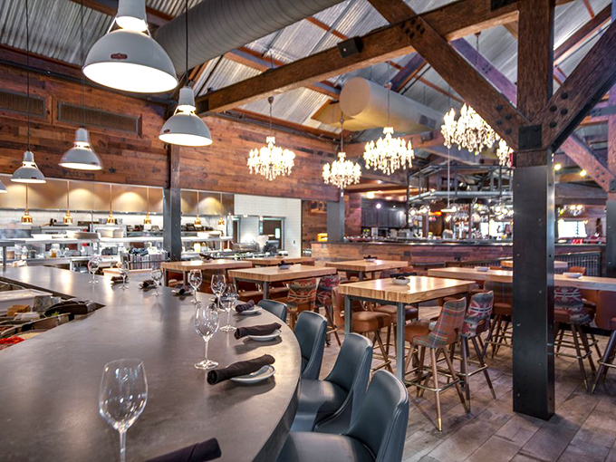 Industrial elegance meets ranch comfort in a space where chandeliers and exposed beams coexist in perfect harmony.