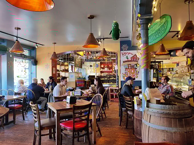 Inside, copper pendant lights cast a warm glow over wooden tables while a pickle-shaped mascot dangles overhead &ndash; a quirky guardian of deli traditions.