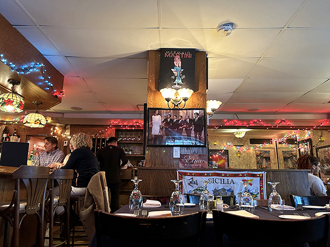 Tiffany-style lamps cast a warm glow over tables while the "SICILIA" banner proudly announces the restaurant's heritage. Comfort meets authenticity.