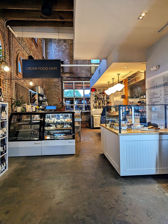 Inside Staplehouse Market, industrial-chic meets warm functionality with exposed brick walls and display cases showcasing culinary treasures.