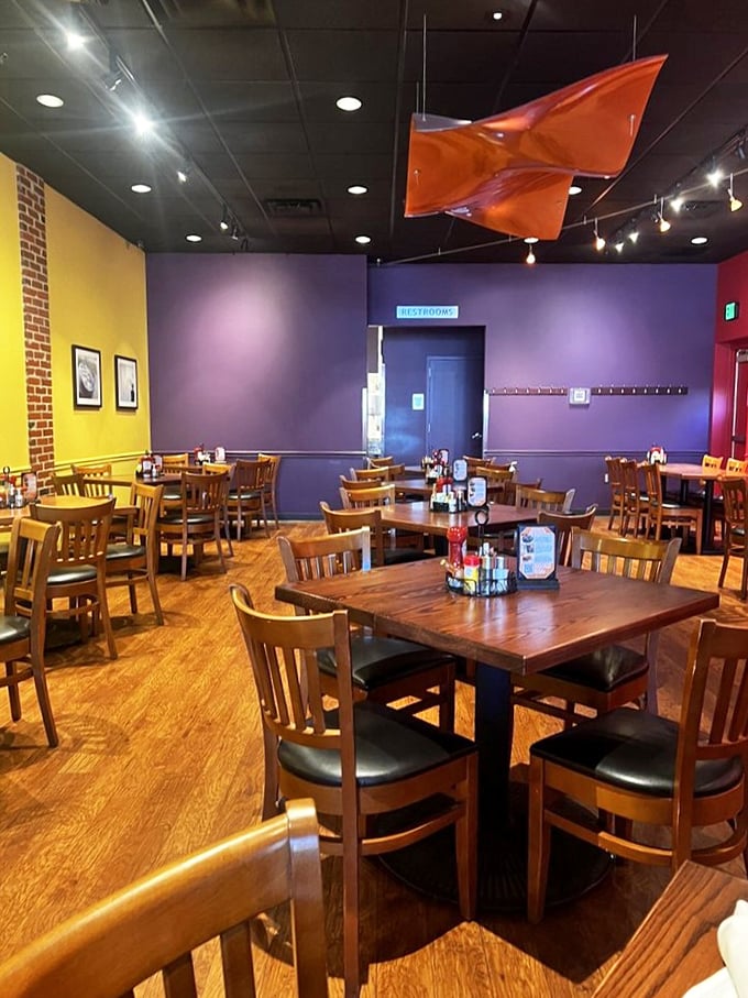 Vibrant purple walls, yellow accents, and that playful orange flag hanging from the ceiling – brunch with personality awaits.