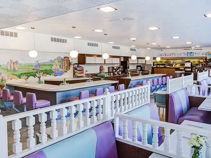 Lavender and teal booths separated by charming white railings create the perfect nostalgic backdrop for your breakfast adventures.