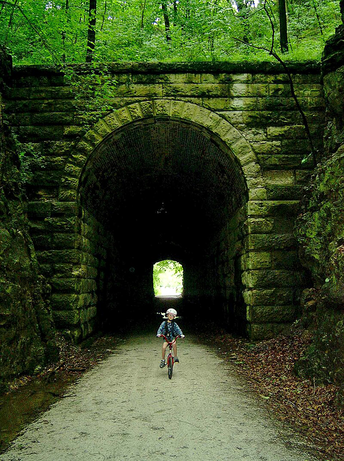 The legendary Katy Trail tunnel beckons cyclists through its stone archway, promising adventure on the other side like a portal to simpler times.