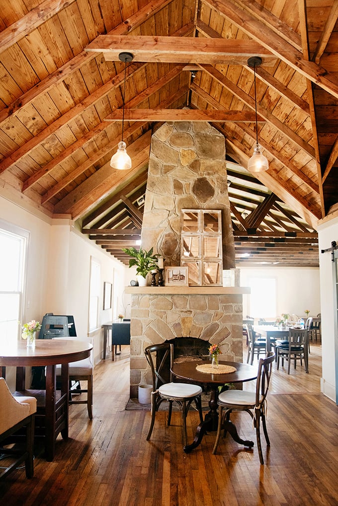 Cathedral-like wooden beams soar overhead while a stone fireplace anchors the space&mdash;architecture that whispers "stay awhile" in the most delicious way possible.