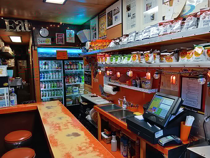 Inside The Squeeze-In, every inch matters. The narrow counter, vintage cooler, and well-worn surfaces tell stories of decades of satisfied customers.