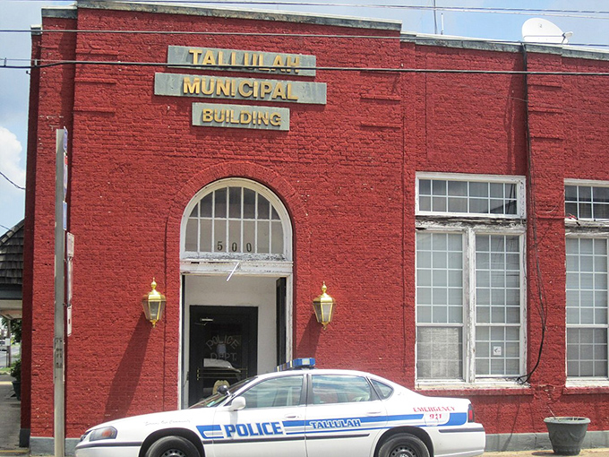 The bright red Tallulah Municipal Building stands as a cheerful sentinel of small-town governance, complete with vintage gold lettering that refuses to go out of style.