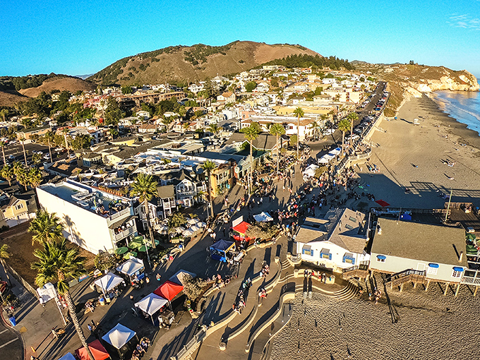 The ultimate beach town aerial view&mdash;colorful buildings, pristine shoreline, and rolling hills creating that perfect California postcard moment that makes you want to cancel your return flight.