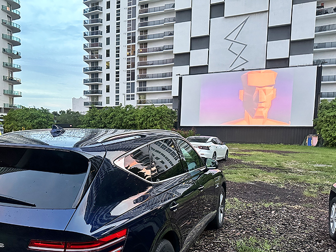 Daytime setup reveals the drive-in's ingenious urban placement, nestled between residential towers with a screen that comes alive when the sun sets.