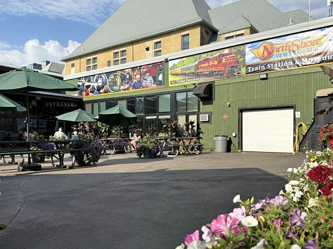 The North Shore Scenic Railroad's welcoming entrance blooms with colorful flowers, promising adventures on rails for visitors of all ages.