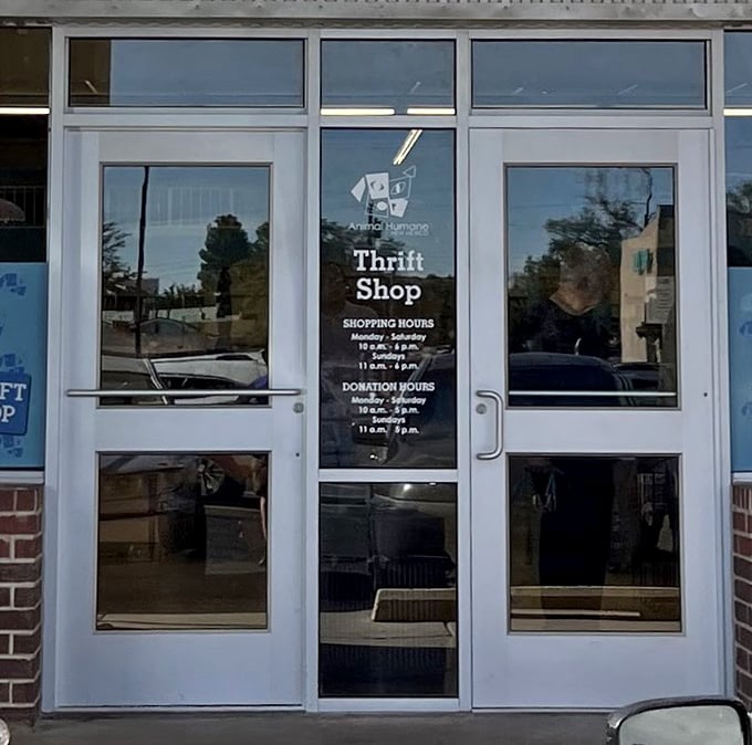 Clear store hours posted on glass doors invite treasure hunters in. The reflection hints at the Albuquerque sunshine waiting outside while you shop.