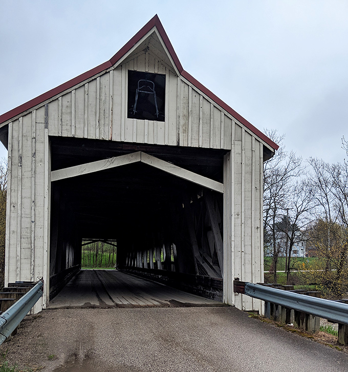 Step into a time machine disguised as a covered bridge. The Mechanicsville Bridge welcomes visitors with its distinctive peaked entrance and weathered charm. 