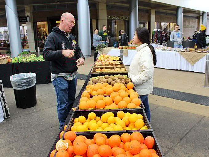 The citrus whisperer at work. A customer engages with a vendor over mountains of perfectly stacked oranges that could brighten even the dreariest desert day.