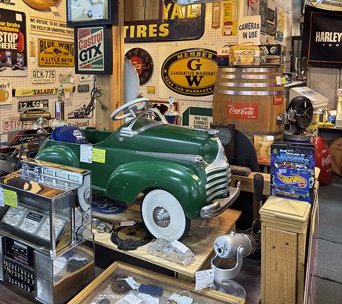 This pristine vintage pedal car isn't just a toy&mdash;it's childhood nostalgia on wheels. Surrounded by classic advertising signs, it's automotive history in miniature form.
