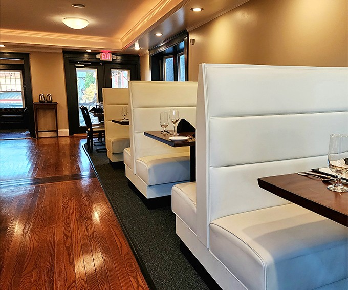 Sleek white booths create intimate dining spaces while polished wood floors add warmth. It's like sitting in a modern interpretation of your grandmother's formal dining room—if grandma were a design genius.