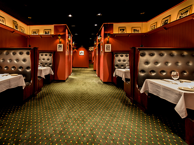 The high-backed leather booths create intimate dining islands where conversations flow as smoothly as the wine and butter.