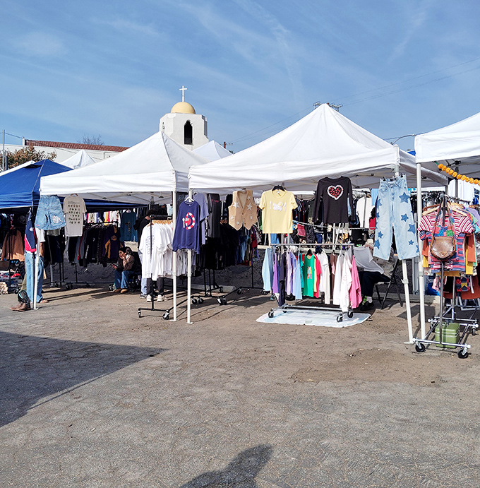 White tents against blue skies create the perfect weekend shopping village. Vintage clothing racks await beneath the watchful dome of a nearby church.