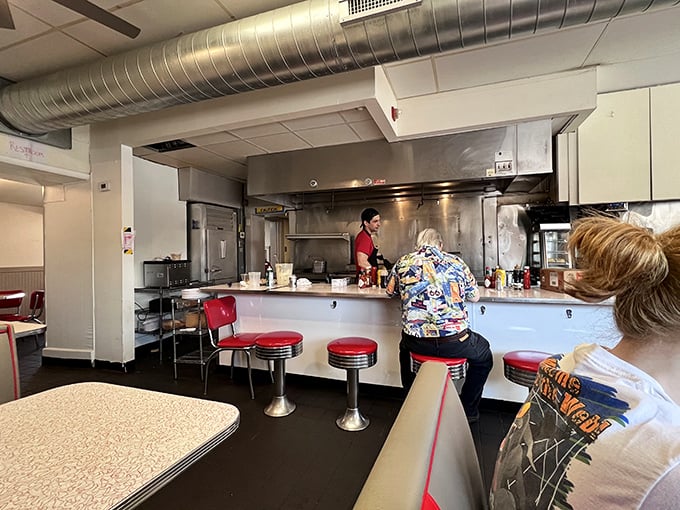 Classic diner counter culture at its finest &ndash; red vinyl stools, gleaming surfaces, and the hypnotic rhythm of short-order cooking that never goes out of style.