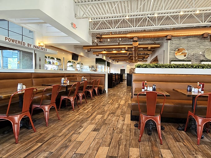 Sunlight streams through the windows, illuminating rustic wooden floors and copper chairs. The "POWERED BY PANCAKES" sign isn't just decor&mdash;it's a mission statement.