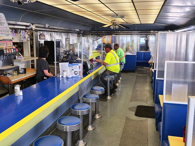 Classic Americana in full display: blue vinyl stools lined up at a sunny yellow-trimmed counter where regulars gather for their morning ritual.
