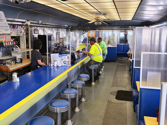 Classic Americana in full display: blue vinyl stools lined up at a sunny yellow-trimmed counter where regulars gather for their morning ritual.