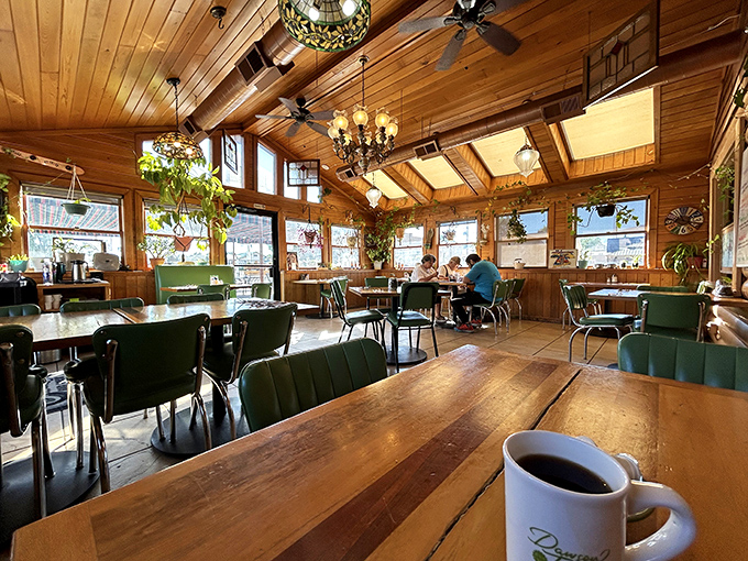 Wood beams, green chairs, and natural light create the kind of cozy breakfast sanctuary your soul desperately needs.
