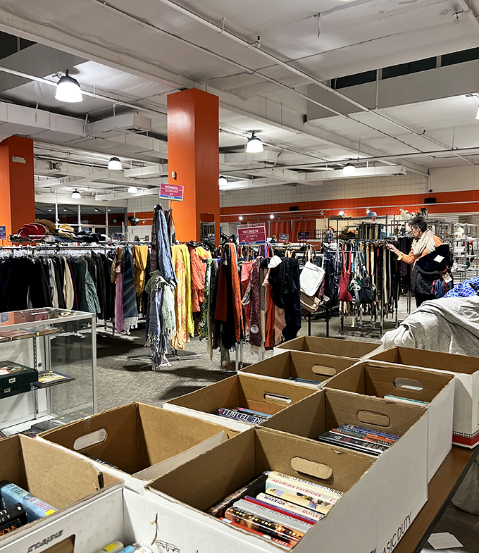 Retail therapy with a conscience! Colorful racks stretch toward industrial ceilings while cardboard boxes await their next literary enthusiasts.