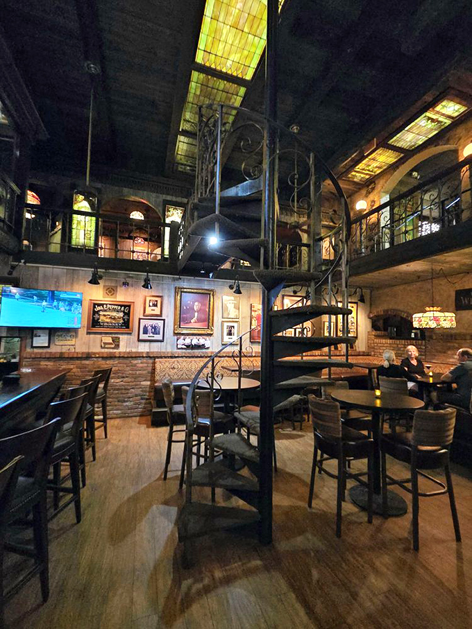 Stained glass ceiling panels cast a honeyed glow across the dining room, while the spiral staircase stands as an iron testament to craftsmanship rarely seen in modern eateries.