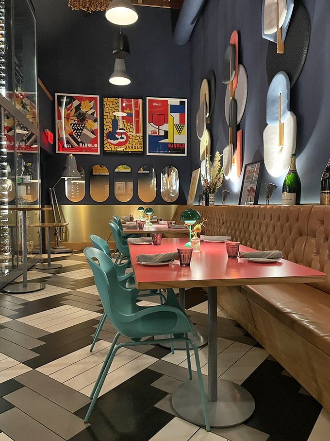 Modern meets rustic in this stylish dining space where navy walls, vintage Italian posters, and turquoise chairs create the perfect backdrop for culinary magic.