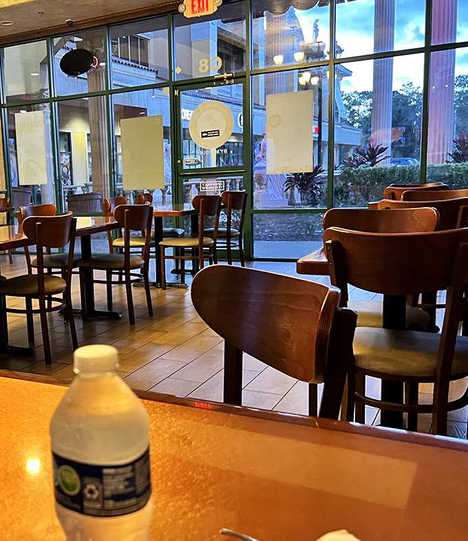 Soft evening light spills through tall windows, casting a gentle glow over wooden chairs that await diners seeking a quiet pause from the day&rsquo;s rush.