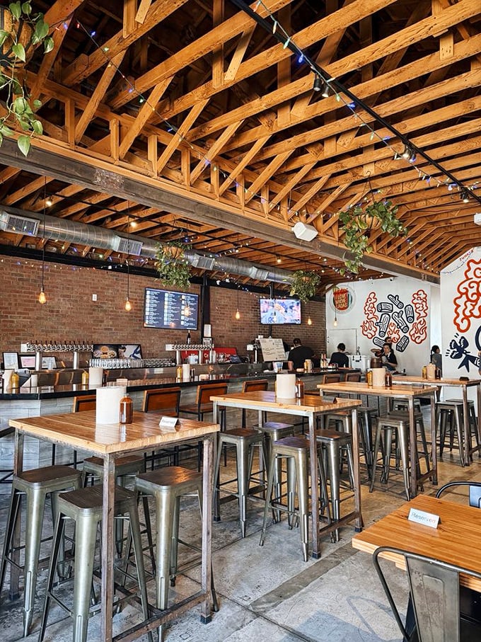 Exposed wooden beams, hanging plants, and industrial-chic vibes create the perfect backdrop for the serious business of barbecue appreciation.