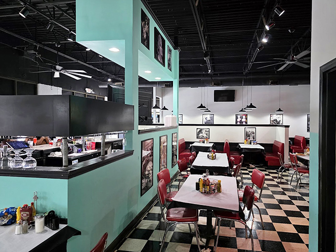 Step into a mint-green time warp where red vinyl booths and checkerboard floors promise comfort before you even taste the food.