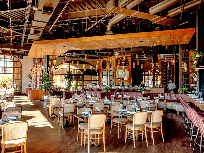 Sunlight streams through expansive windows, dancing across wooden tables while exposed beams create the perfect backdrop for memory-making meals.