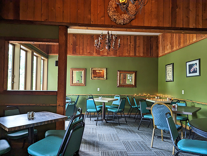 Sage green walls meet wooden beams in this cozy dining room where vintage-framed mirrors reflect both light and satisfied smiles from happy diners.