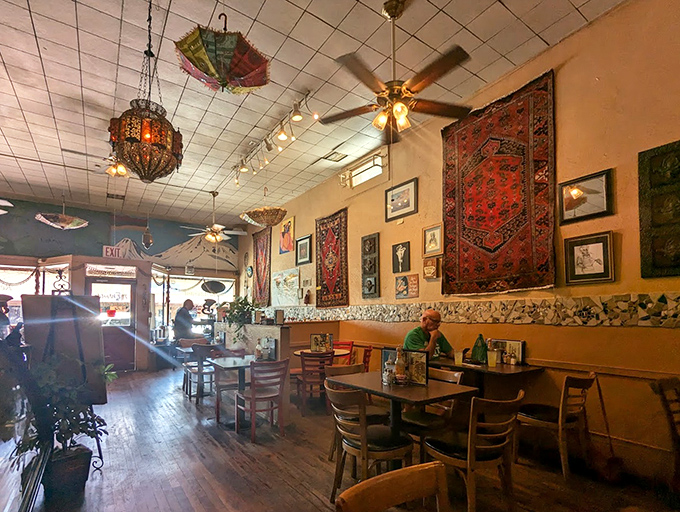 This interior could star in a Norman Rockwell painting – rugs on walls, lanterns overhead, and that perfect diner patina.