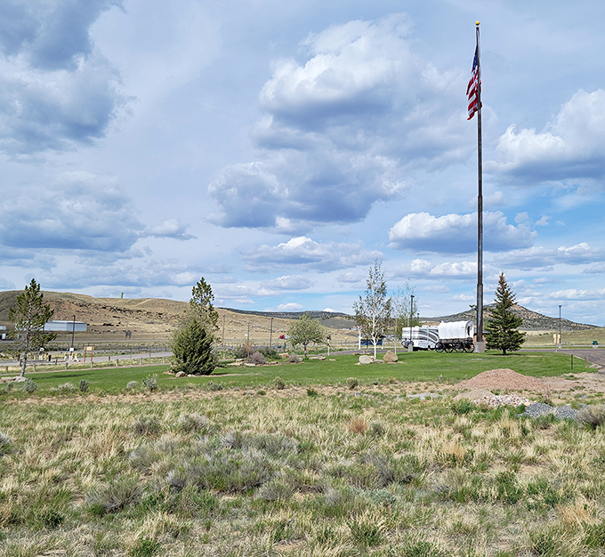 Wyoming's big sky country unfurls before you, where the American flag stands proud against a canvas of clouds and prairie.