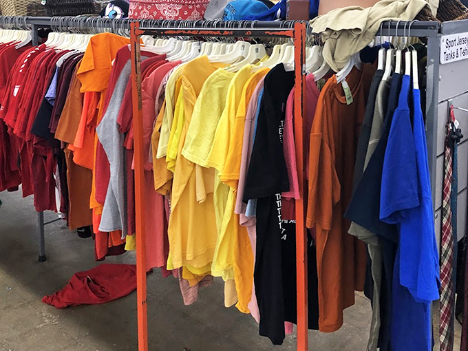 A rainbow of t-shirts hangs in perfect chromatic order, like a fashionable sunset where every color represents a different bargain waiting to be claimed.