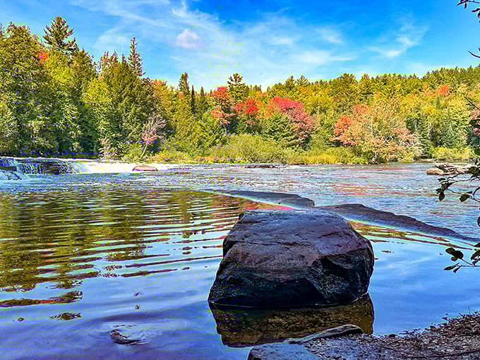 Tranquility meets drama where a single rock stands sentinel in the Lower Falls area, surrounded by the first hints of autumn's color palette.