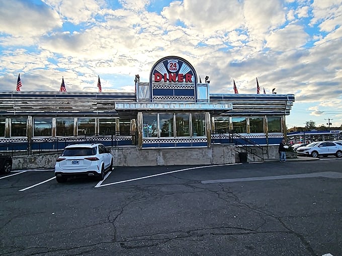 Blue Colony Diner stands proud against the Connecticut sky, its neon promising "24 hours" of comfort food possibilities. Those American flags add a touch of hometown pride to your midnight meatloaf mission.