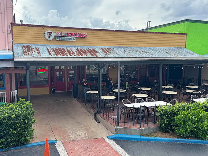 Flippers' weathered metal roof and sunny yellow exterior scream "vacation pizza spot." The outdoor seating practically begs you to people-watch.