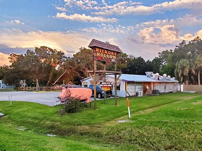 Hickory Hollow's rustic sign and pink pig mascot against the sunset sky. BBQ poetry doesn't need fancy words, just good smoke.